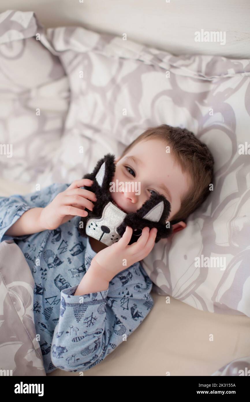 Happy boy with sleep mask lying on bed Stock Photo - Alamy