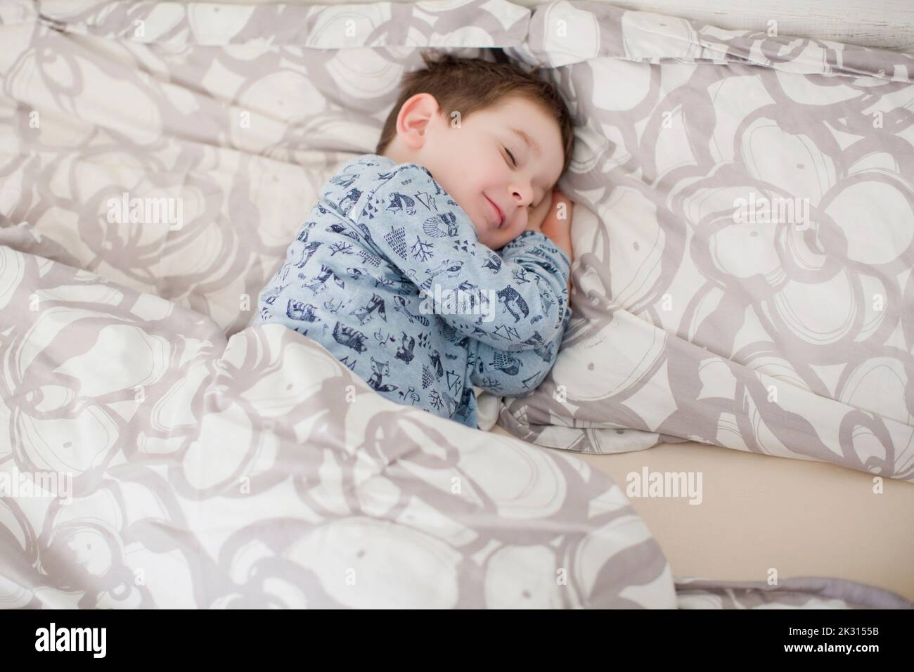 Smiling boy sleeping on bed Stock Photo - Alamy
