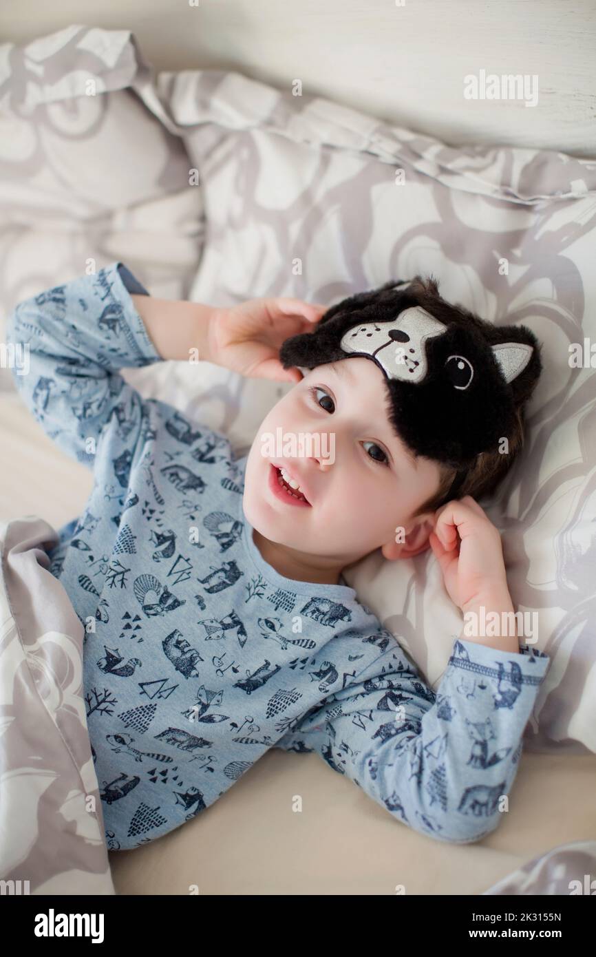 Boy with sleeping eye mask lying on bed Stock Photo - Alamy