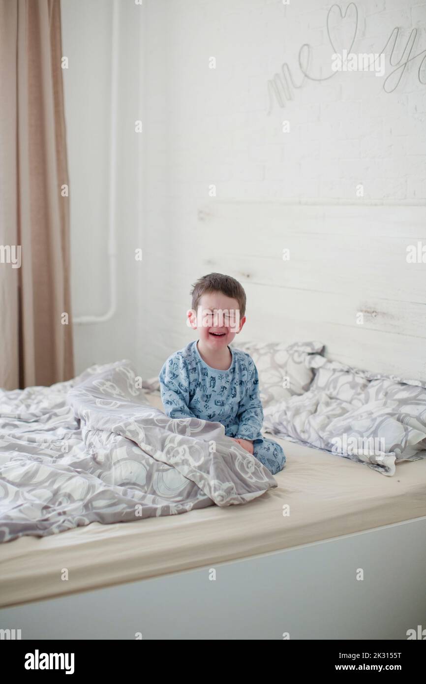 Crying boy sitting on bed Stock Photo - Alamy