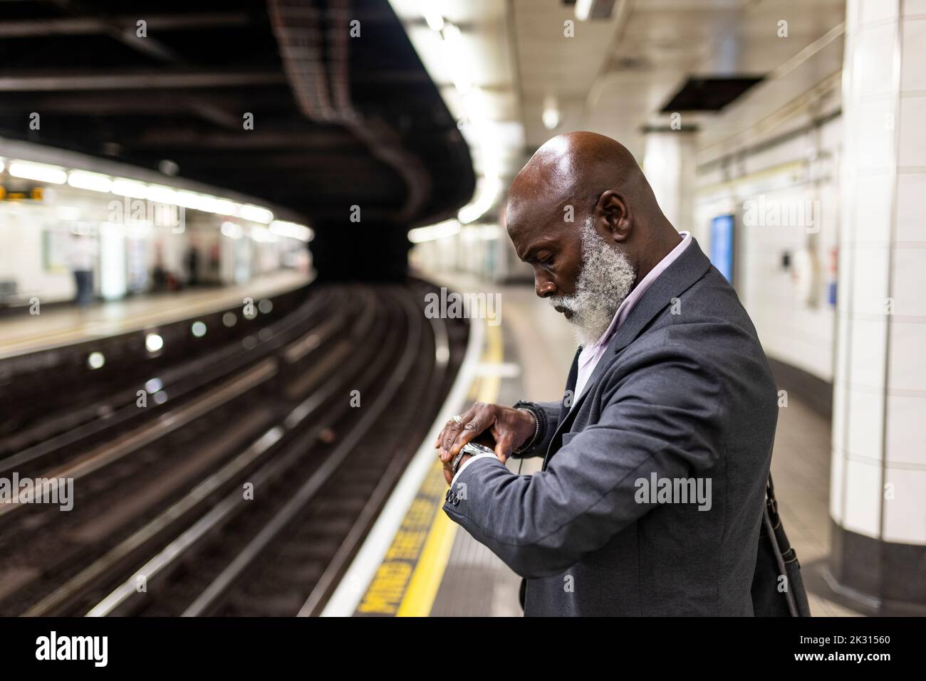 Senior businessman checking time on wristwatch waiting at subway ...