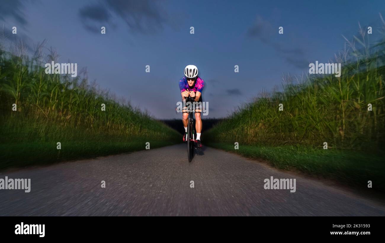 Sportsman riding racing bicycle on road at dusk Stock Photo - Alamy