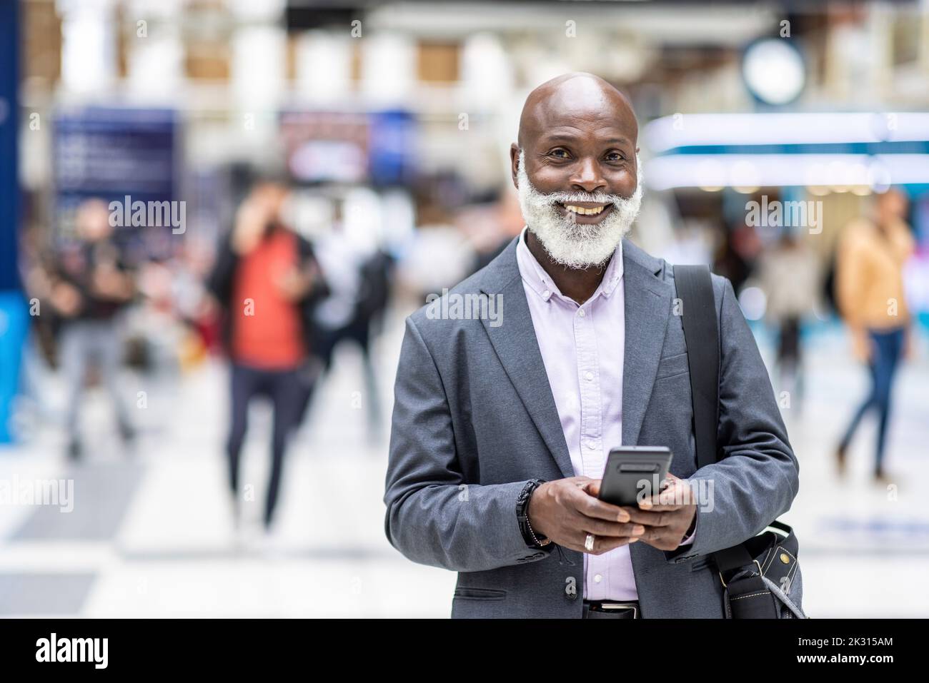 Smiling bald commuter with mobile phone at railroad station Stock Photo ...