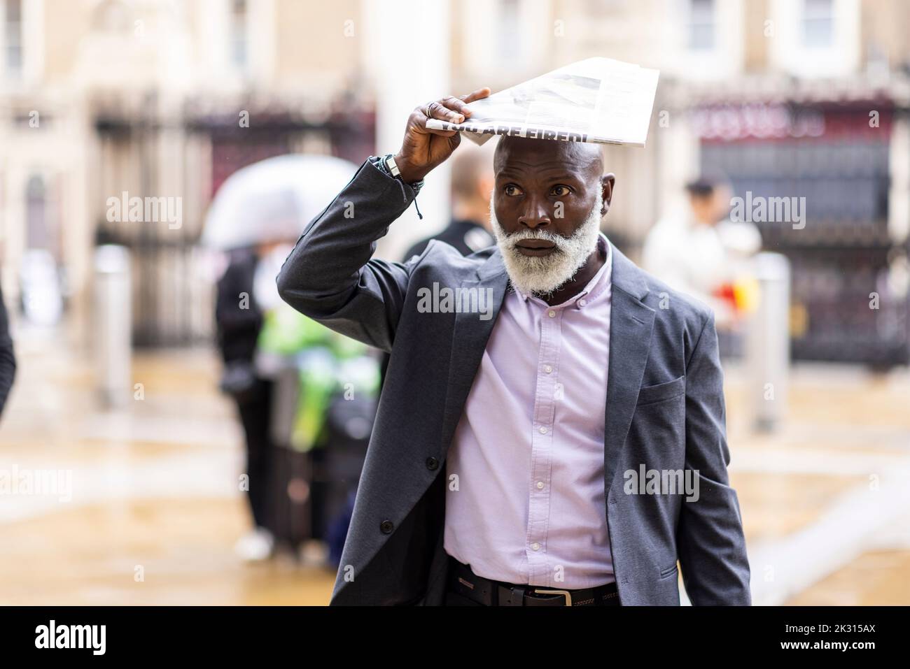 Senior businessman covering head with newspaper on rainy day Stock ...