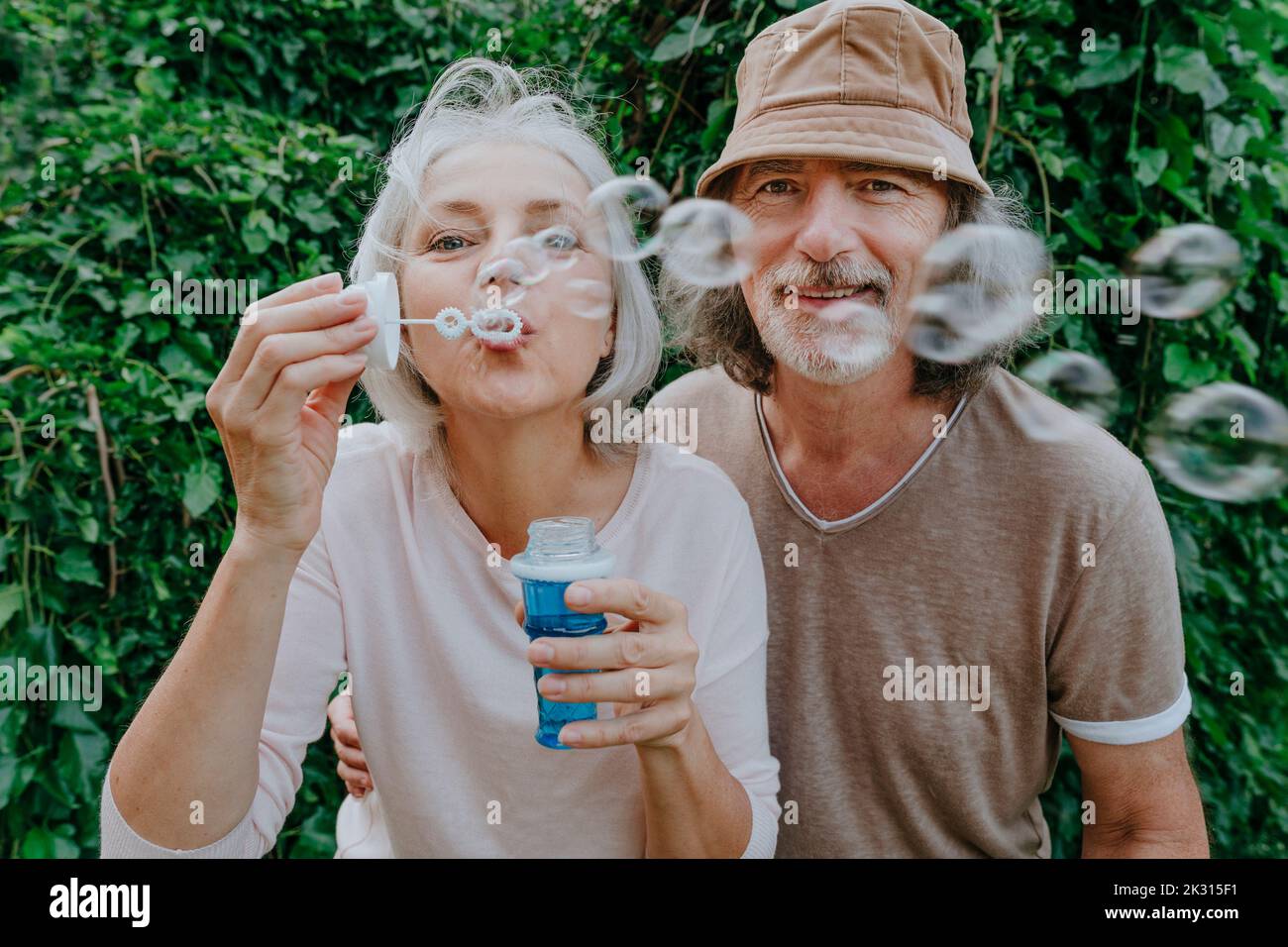 Mature woman making bubbles by senior man in park Stock Photo - Alamy