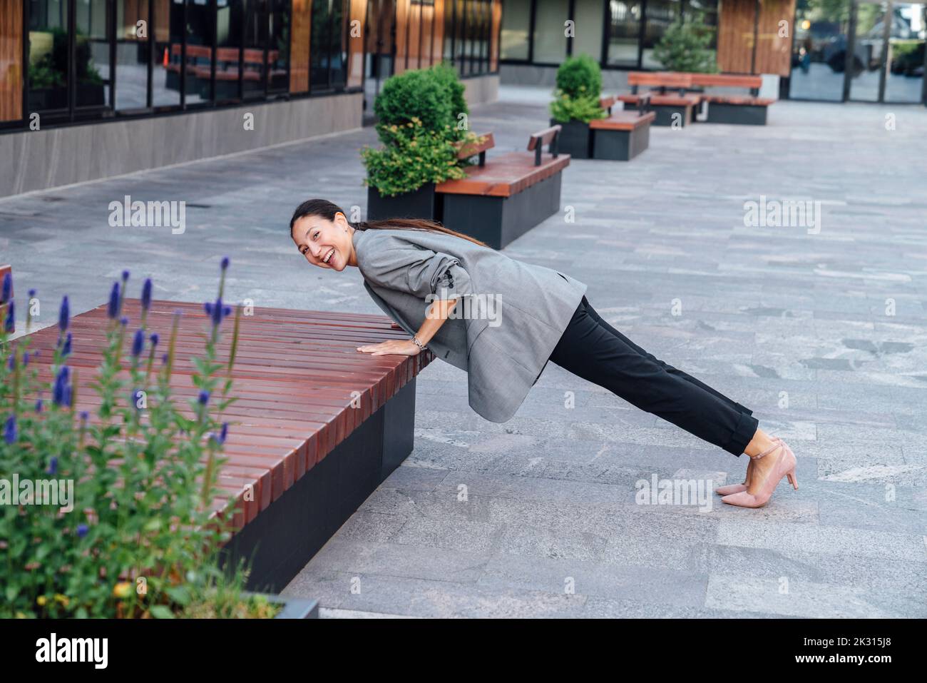 Happy businesswoman practicing push-ups on bench at office park Stock ...