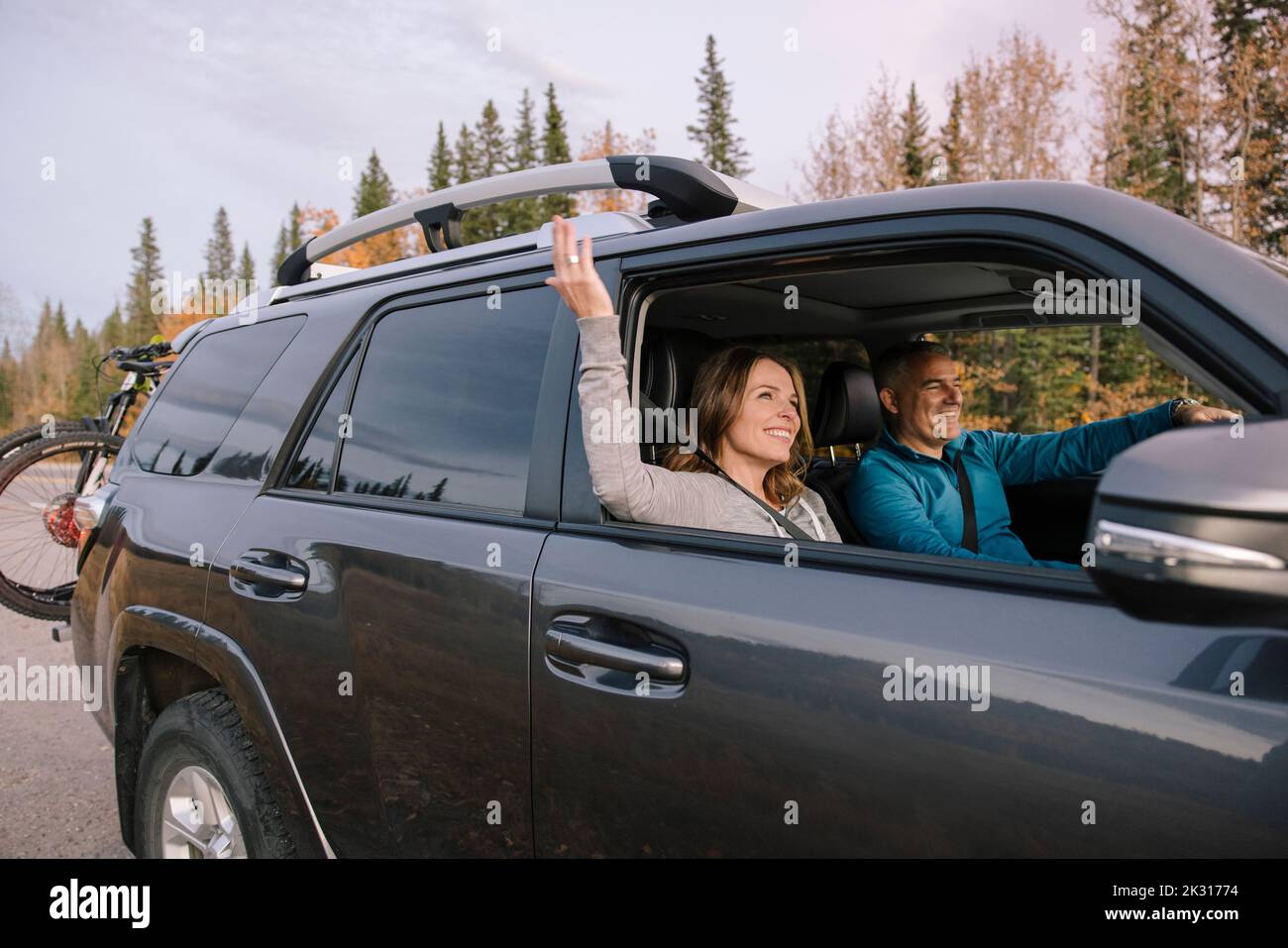 Couple driving SUV through forest Stock Photo - Alamy