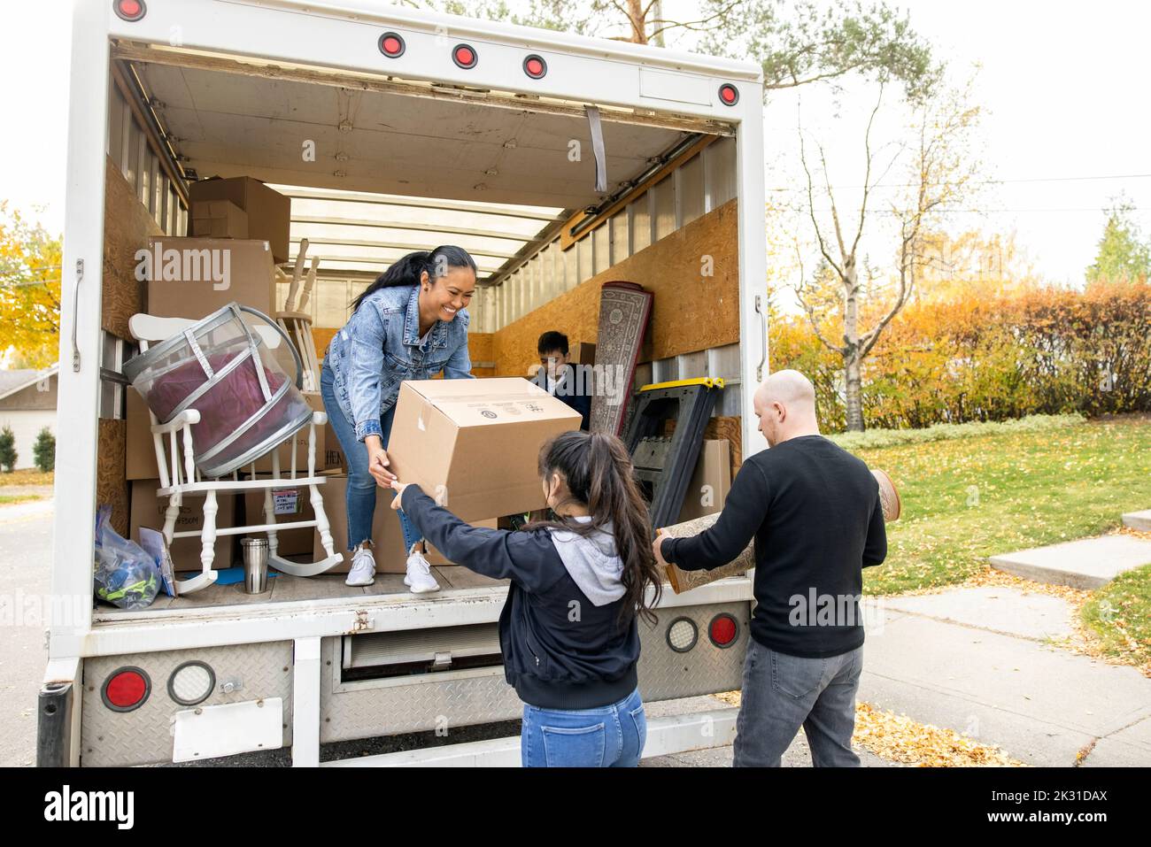Family unloading belongings from back of moving van Stock Photo - Alamy