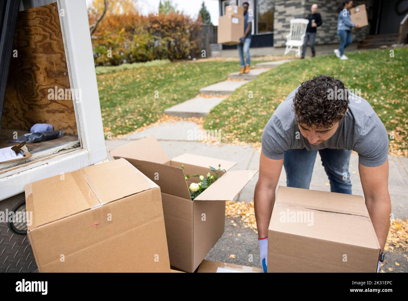 Male mover lifting boxes at back of moving van Stock Photo - Alamy
