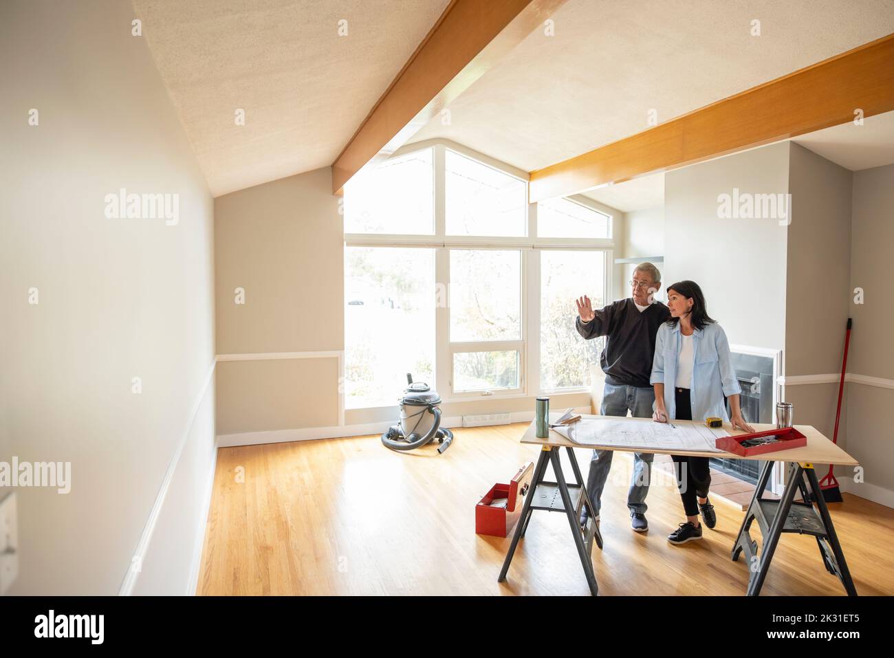 Architect and client discussing blueprints in home under renovation ...
