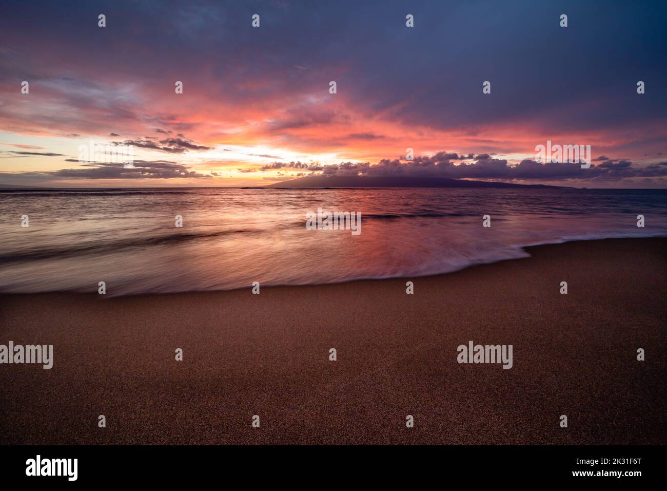Sandy beach in Maui, Hawaii with smooth waves and sunset in background ...