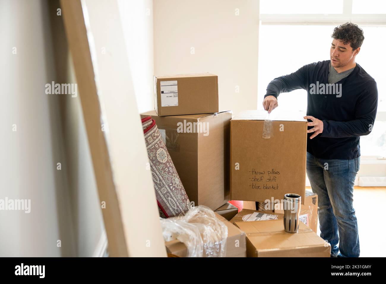 Man unpacking cardboard moving box in new home Stock Photo - Alamy