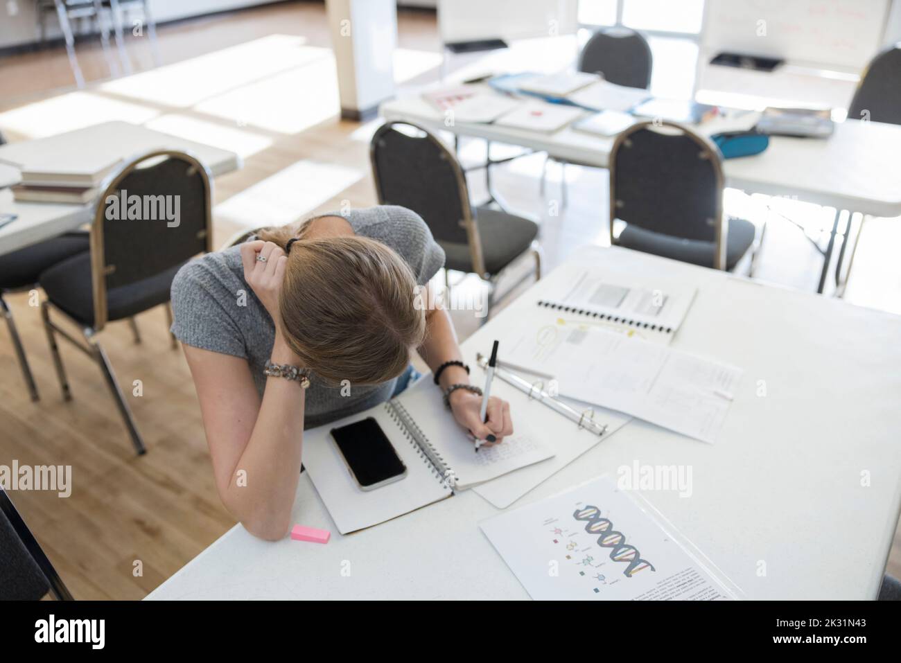 Focused high school girl student doing homework in study hall classroom ...