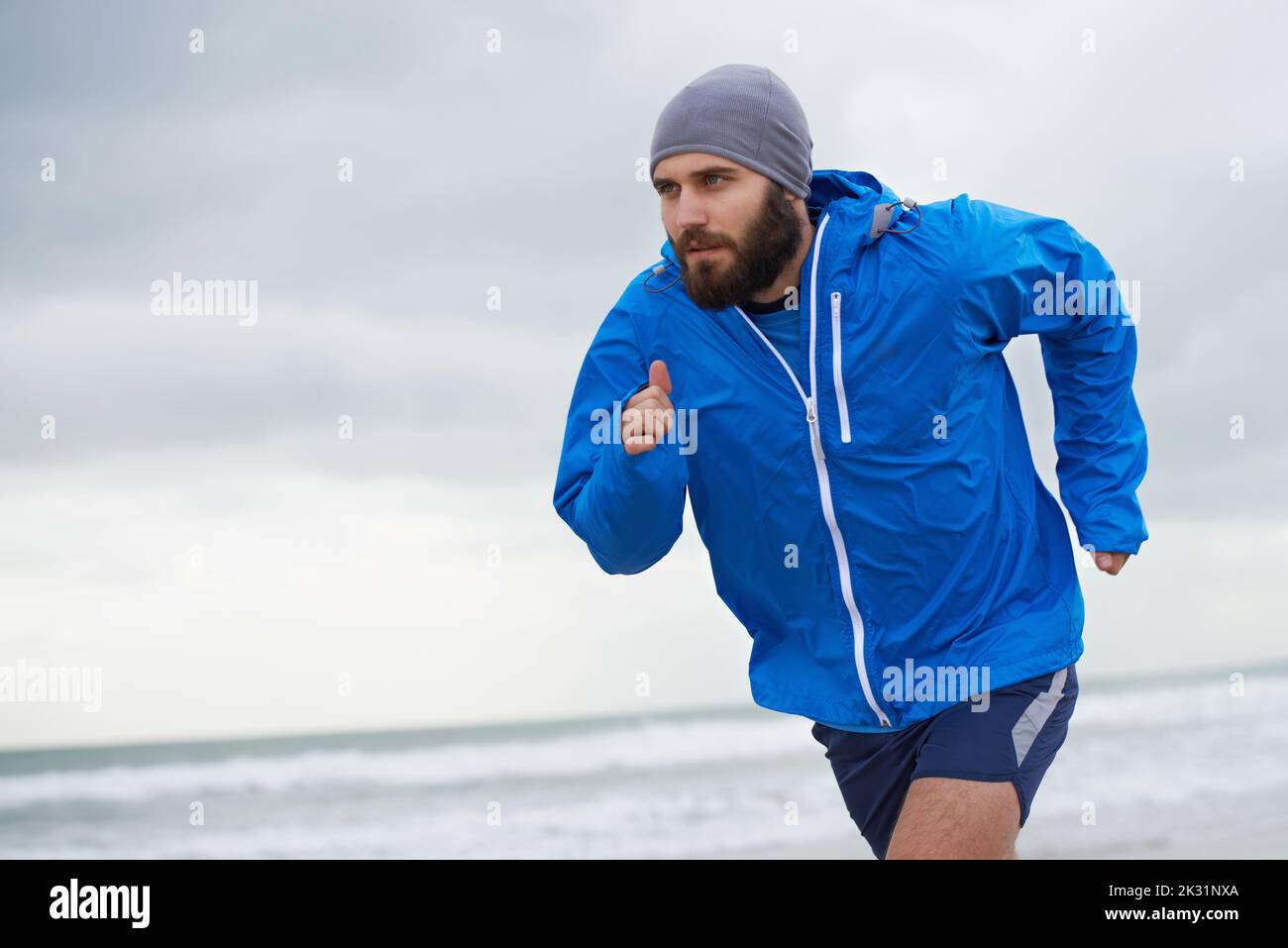 Taking a morning run on the beach. a handsome young man running on the ...