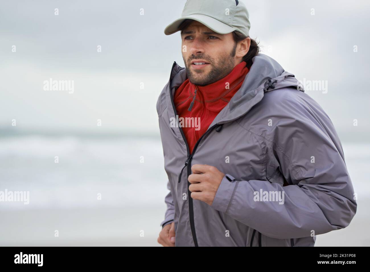Taking a morning run on the beach. a handsome young man running on the ...