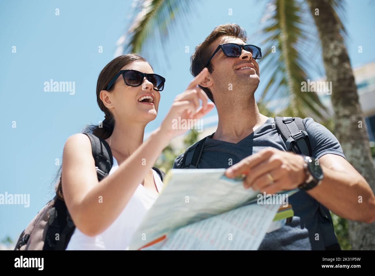 Discussing where to go next. a young couple looking at a map while ...