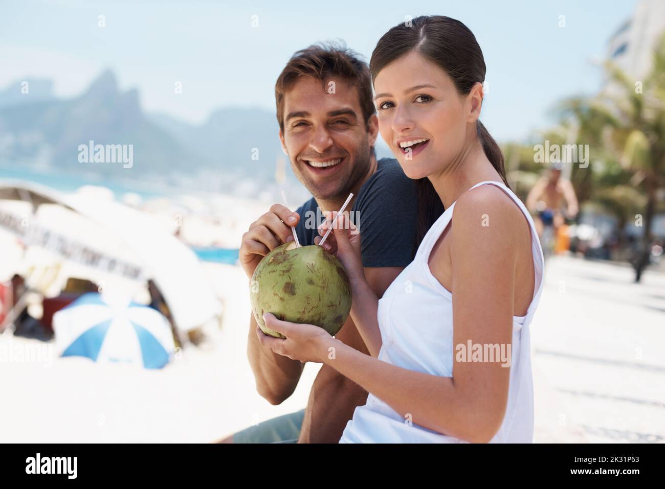 Relaxing on a tropical vacation. Young couple enjoying a drink from a ...
