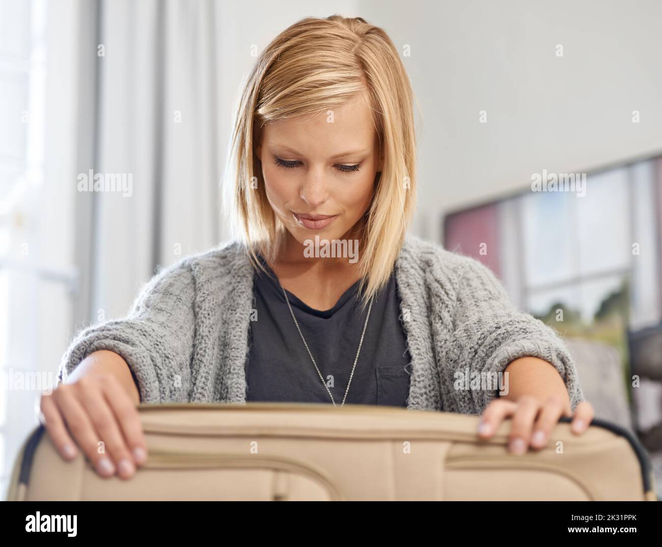 Getting ready for her vacation. a young woman packing her suitcase ...
