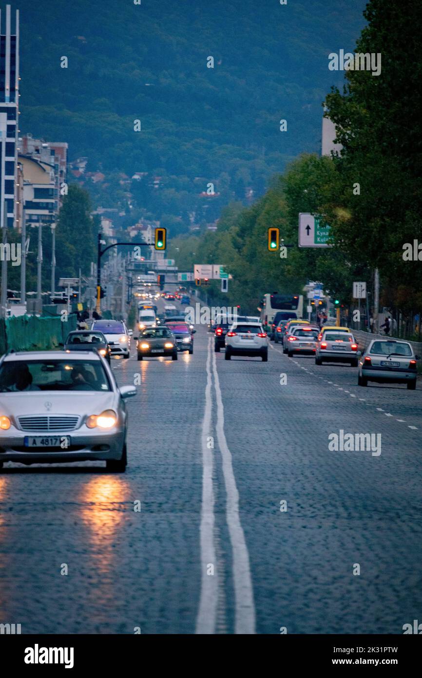 A vertical shot of a crowded road with driving cars and lush trees in ...
