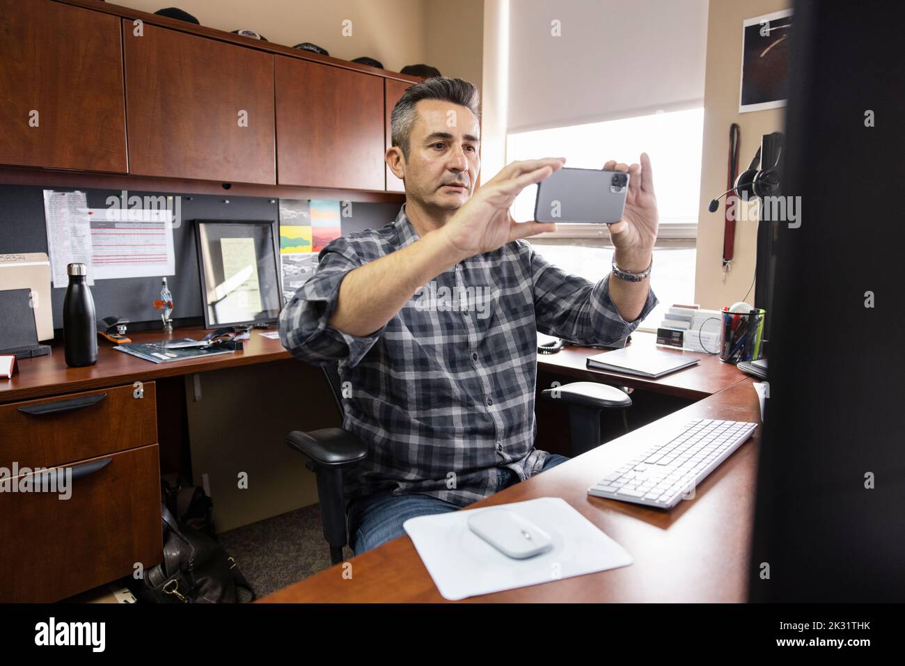 Man taking photo of computer screen in office Stock Photo - Alamy