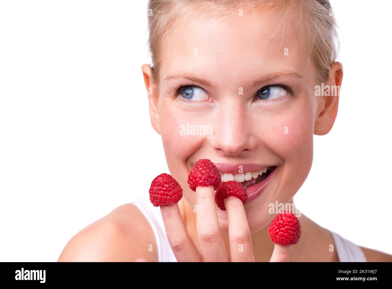 Berry playful. a beautiful young woman playfully eating raspberries off ...