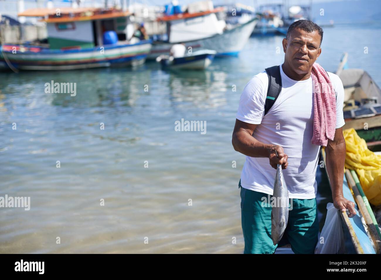 Fishing is my life. Portrait of a fisherman standing with a fish next ...