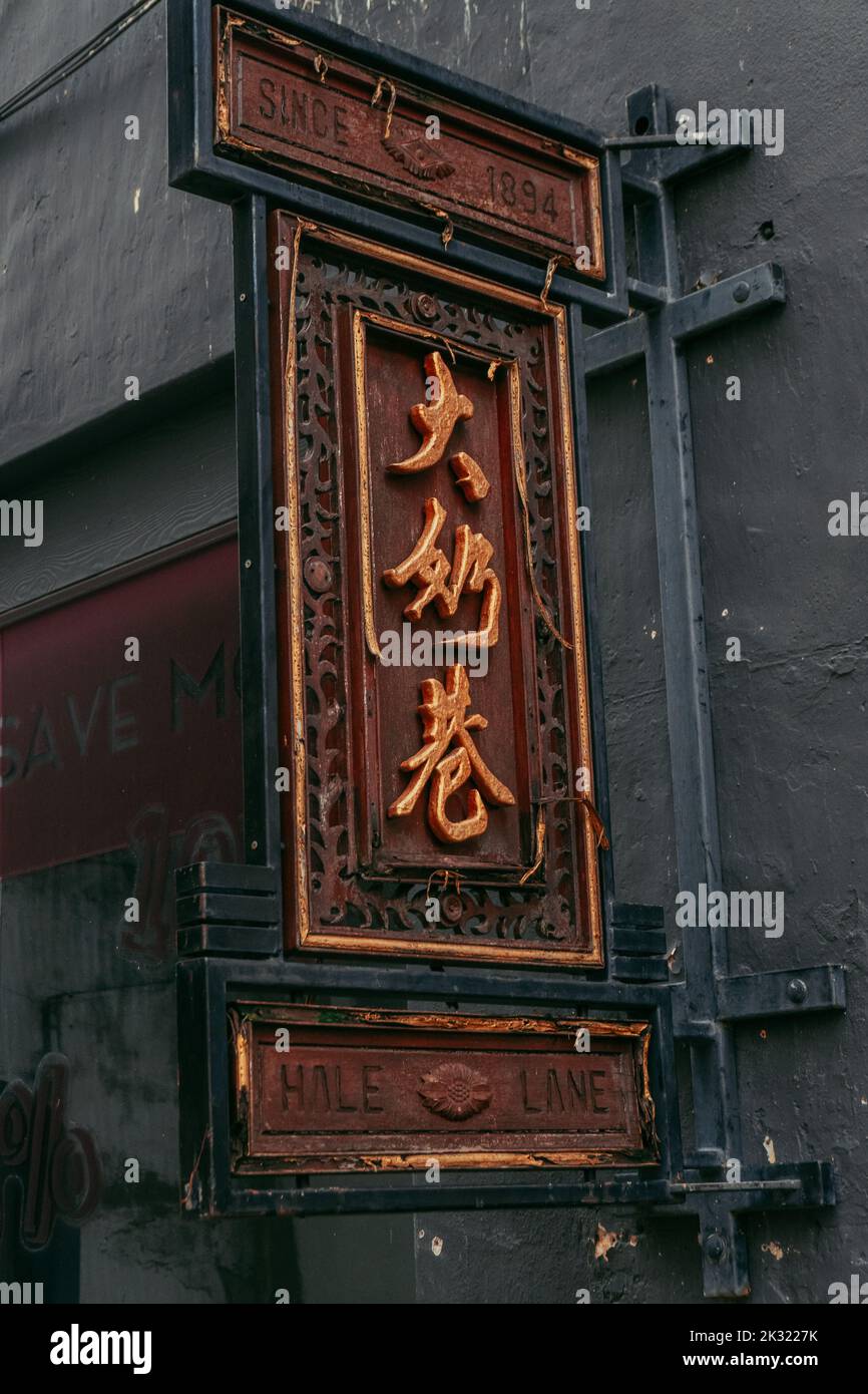 A vertical shot of golden and maroon sign on black building with Asian ...