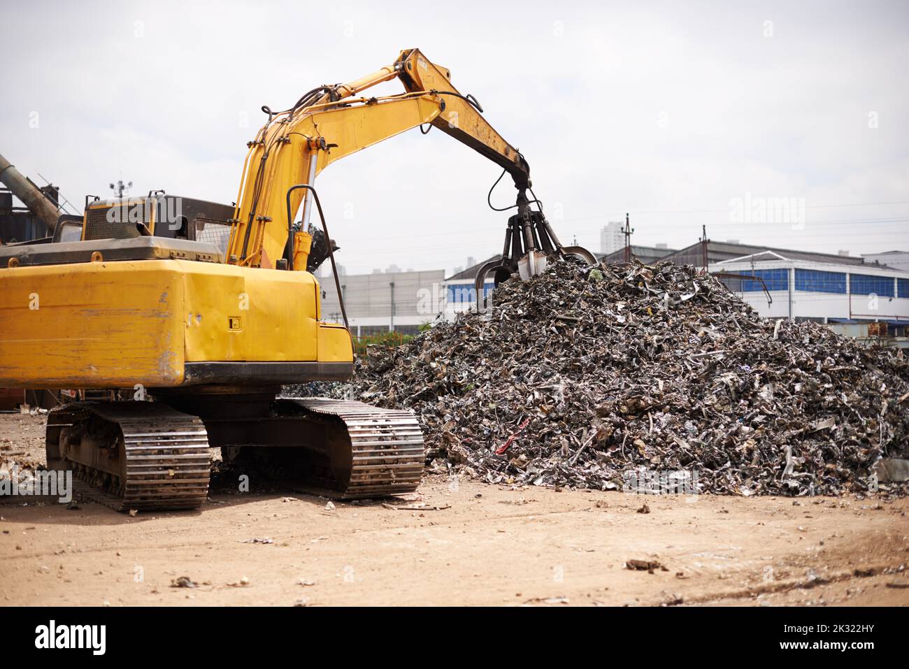 It jsut keeps piling up. a crane at work in a dumpsite Stock Photo - Alamy