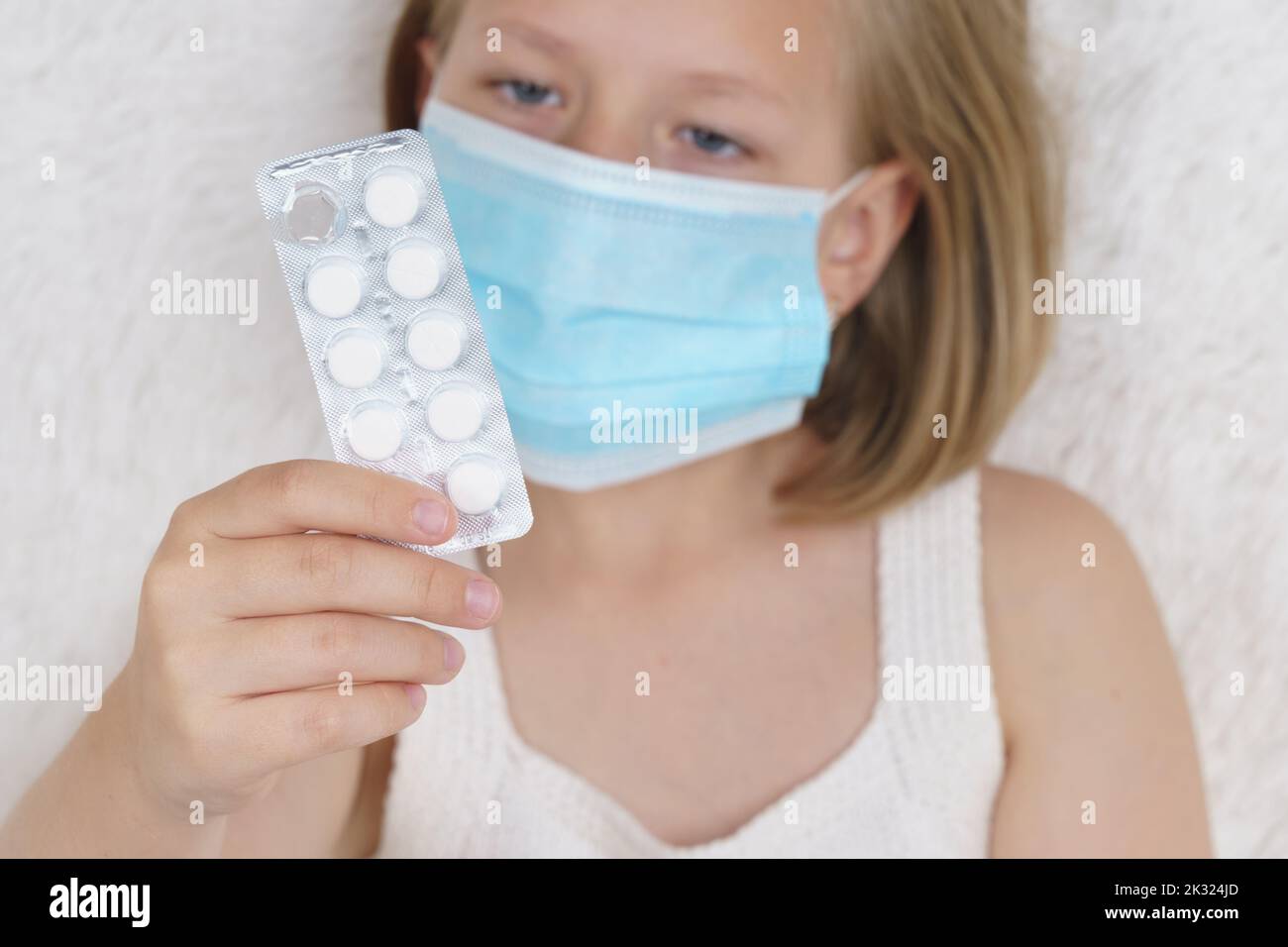 Sick teenage girl is looking through the packaging with pills. Medical ...