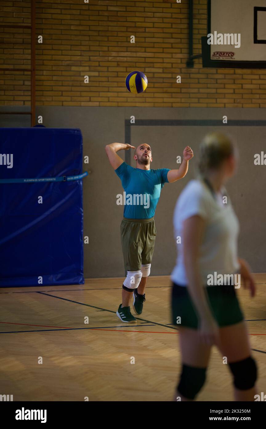 A vertical shot of a young male playing volleyball during a game in an ...