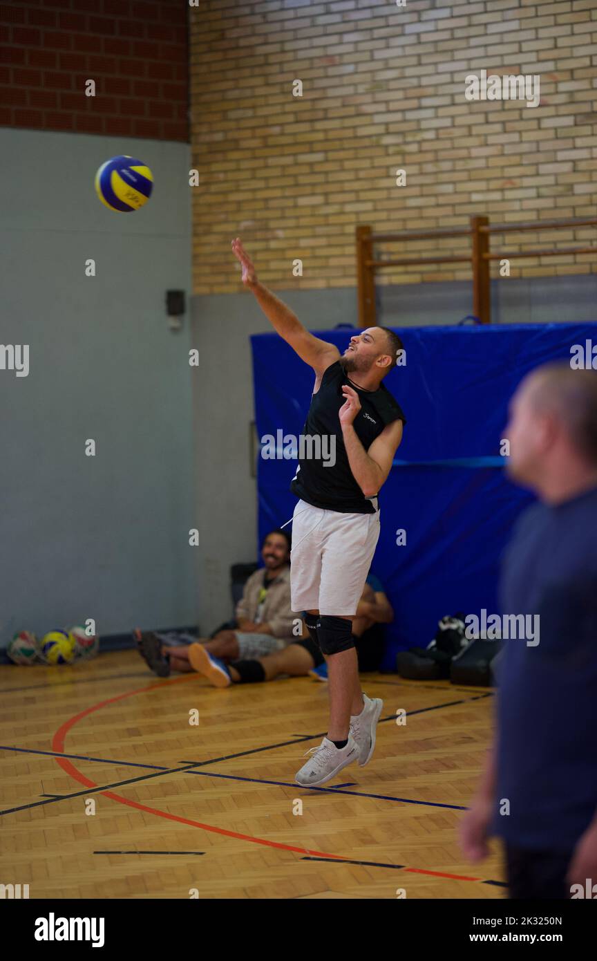 A vertical shot of a young male playing volleyball during a game in an ...