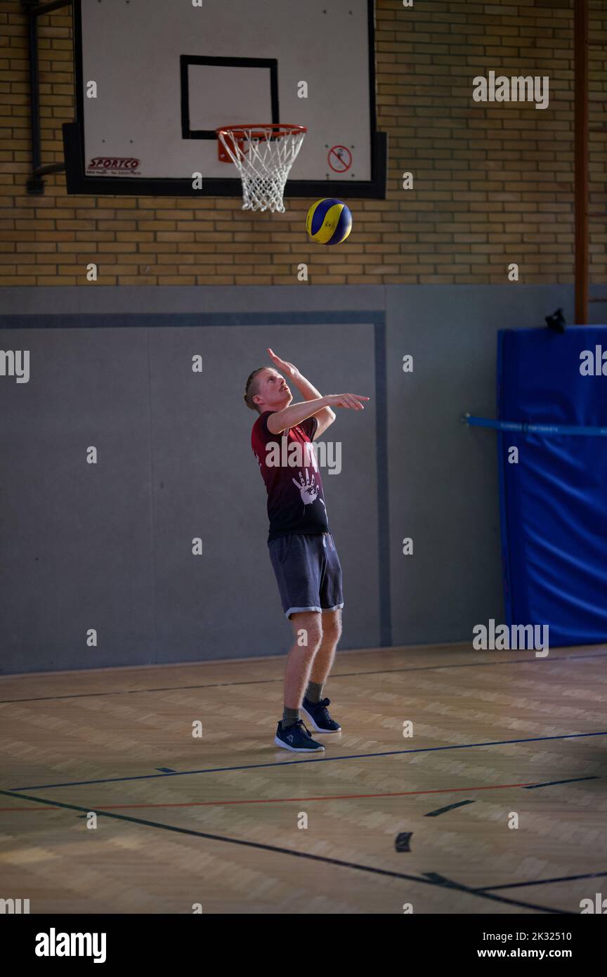A vertical shot of a young male playing volleyball during a game in an ...