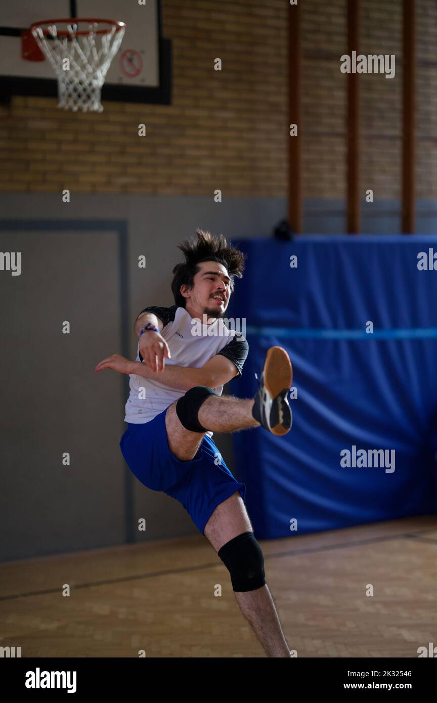 A vertical shot of a young male playing volleyball during a game in an ...