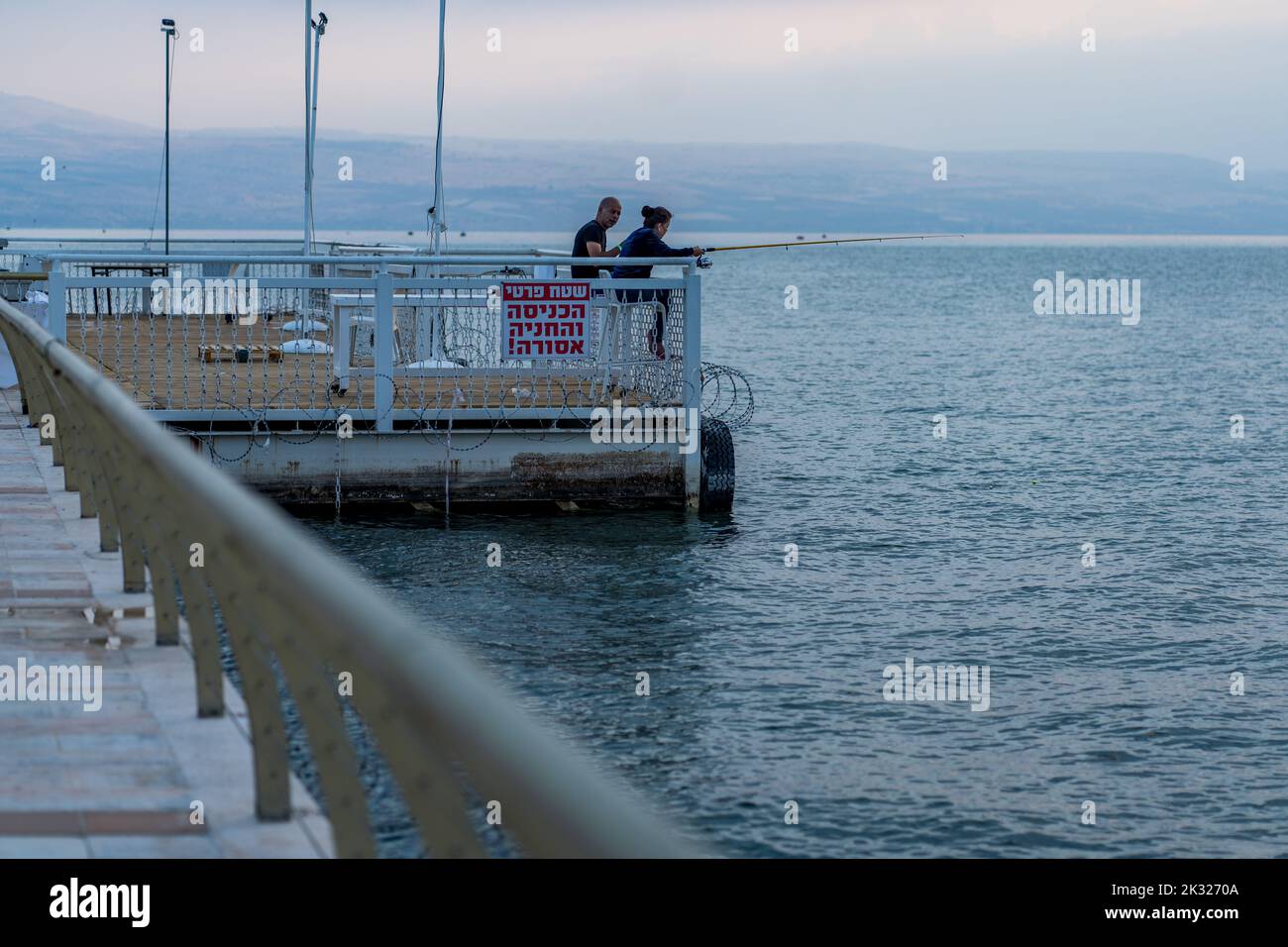A side shot of a male and female standing on the boardwalk with a metal ...
