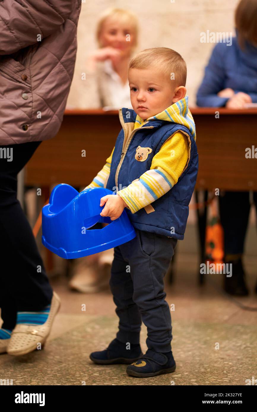 A little boy carries a potty toilet, which he received at the ...