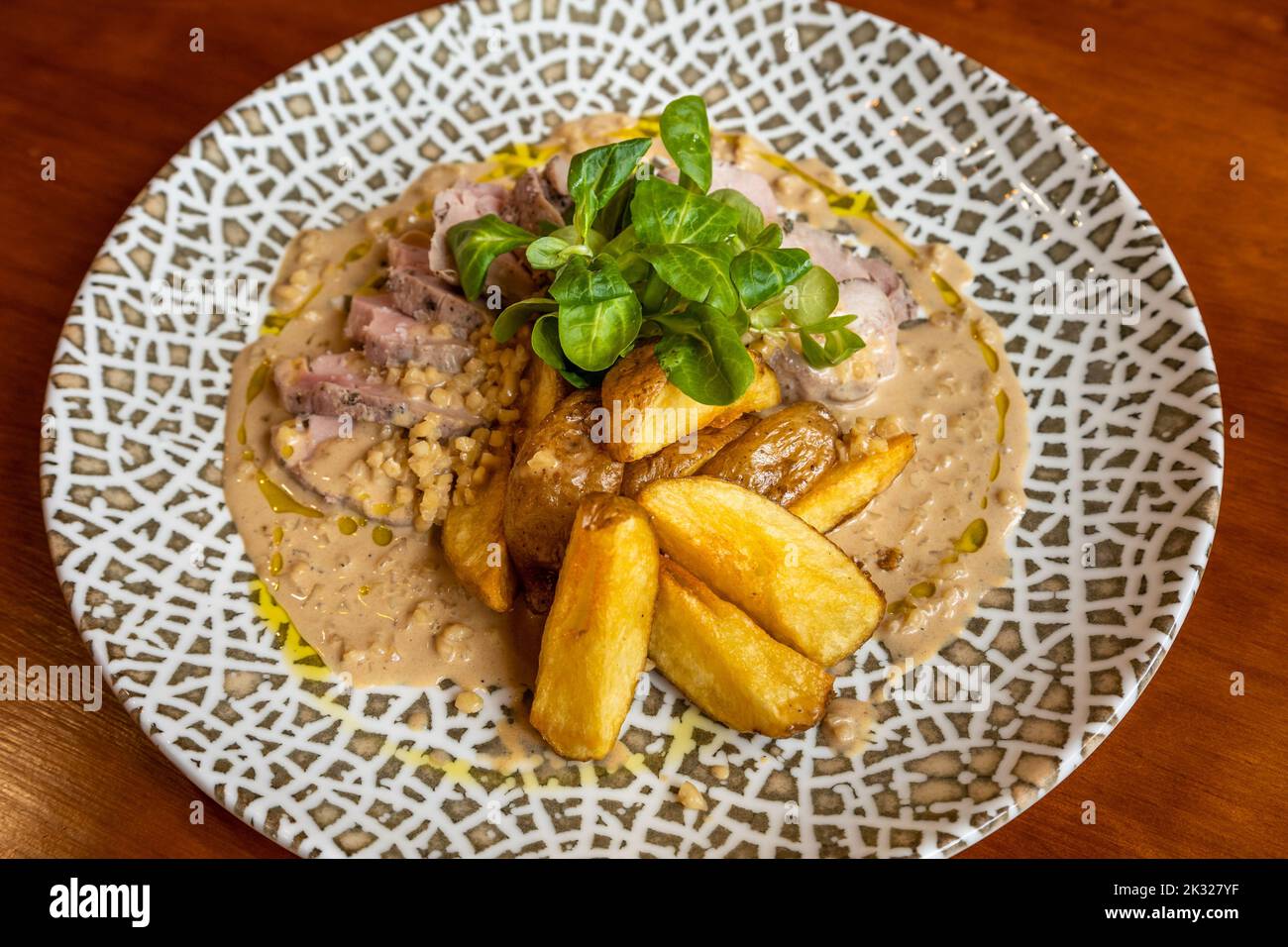 A plate of creamy beef stew with fries and herbs Stock Photo - Alamy
