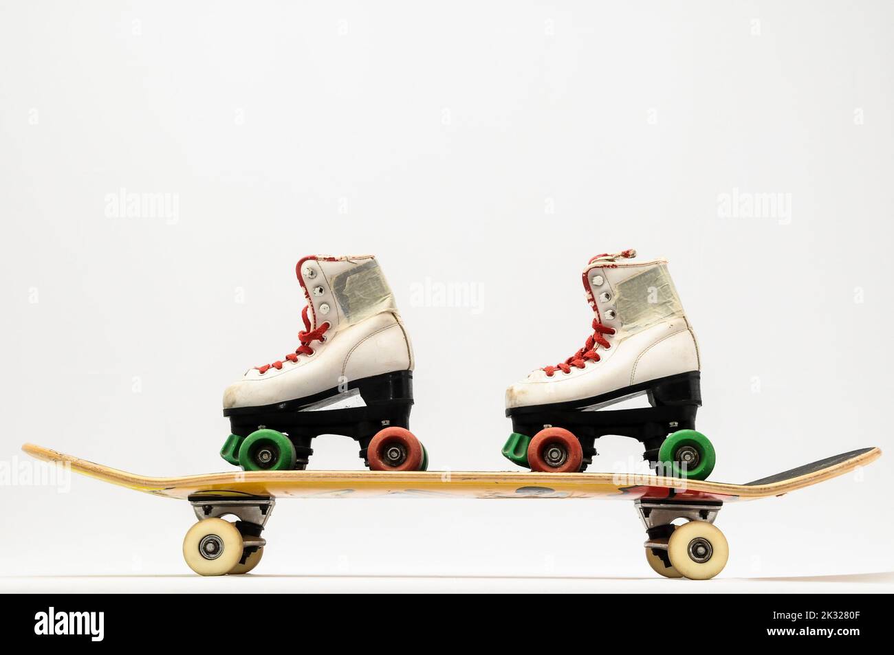 Two white rollerskates with colorful wheels on a skateboard on white ...