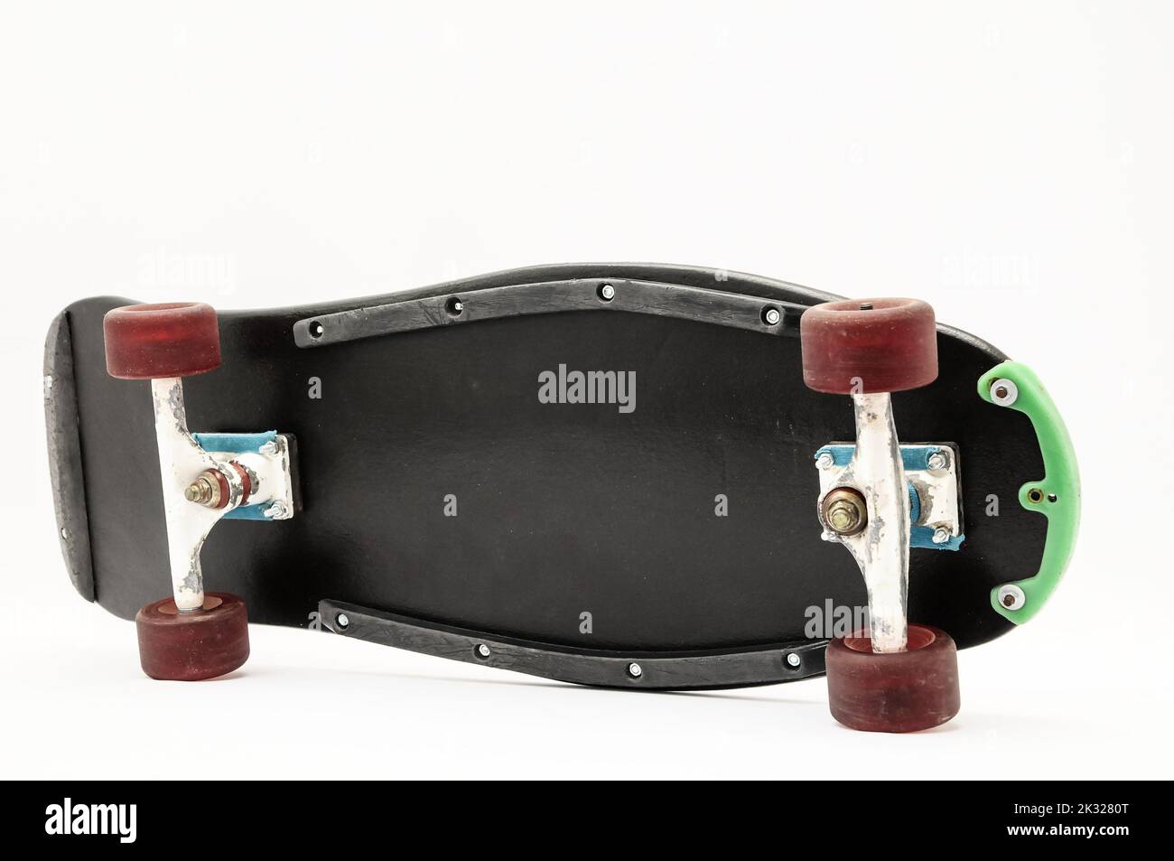 A vintage style black skateboard with maroon wheels isolated on white ...