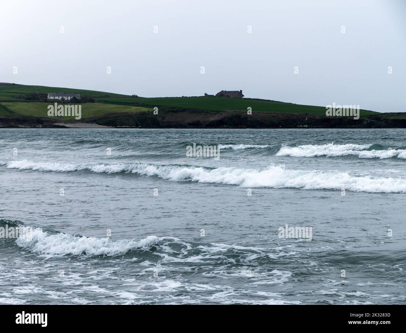 Sea at high tide. A building on a hill on the seashore. Gray gloomy sky ...