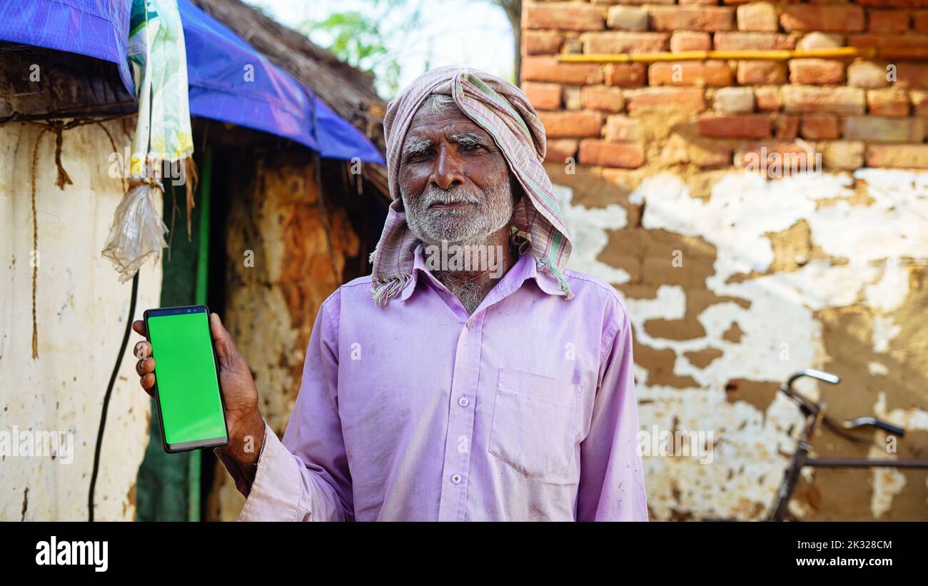 Indian old man holding a mobile phone and point towards it's screen ...