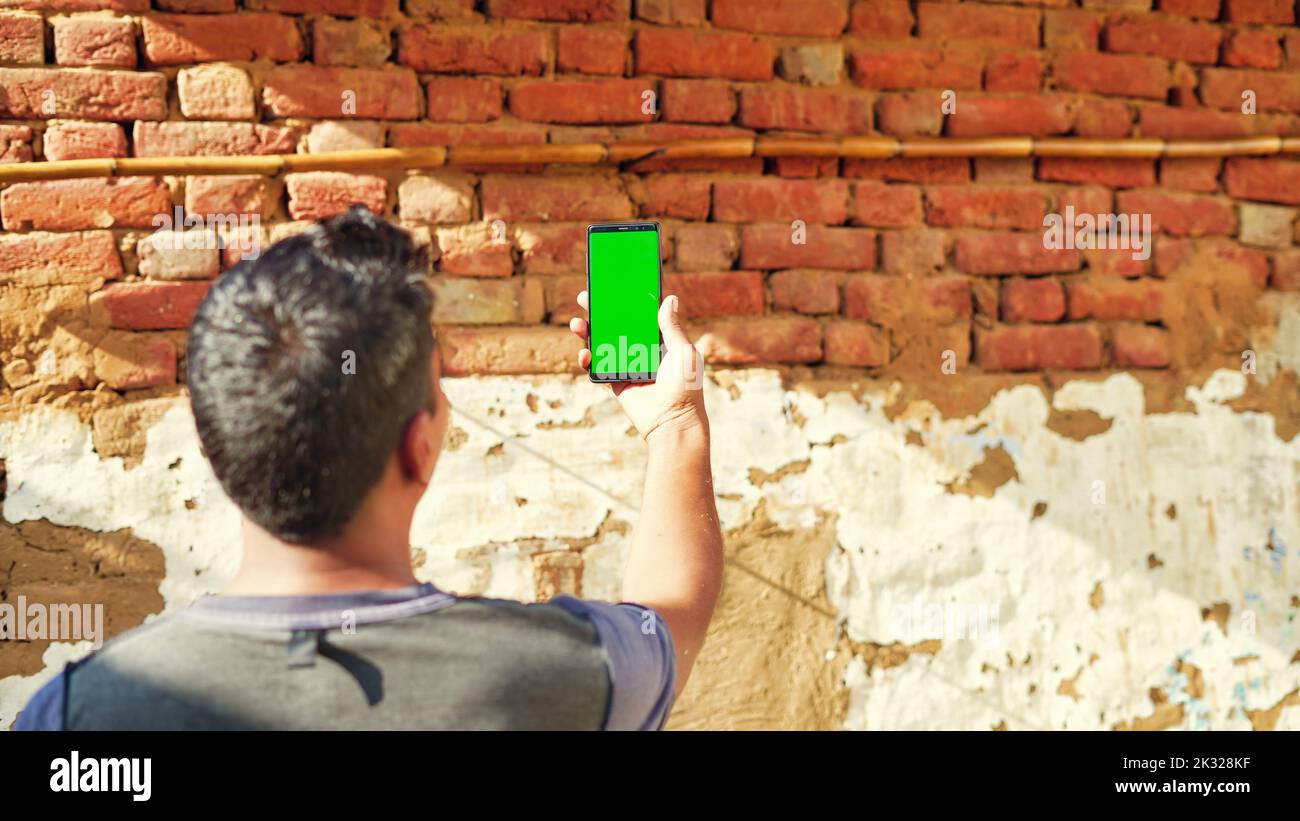 Young Indian man taking selfie and showing a green screen cell phone ...