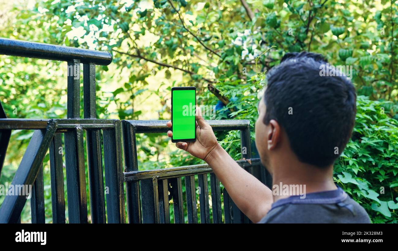Young Indian man taking selfie and showing a green screen cell phone ...