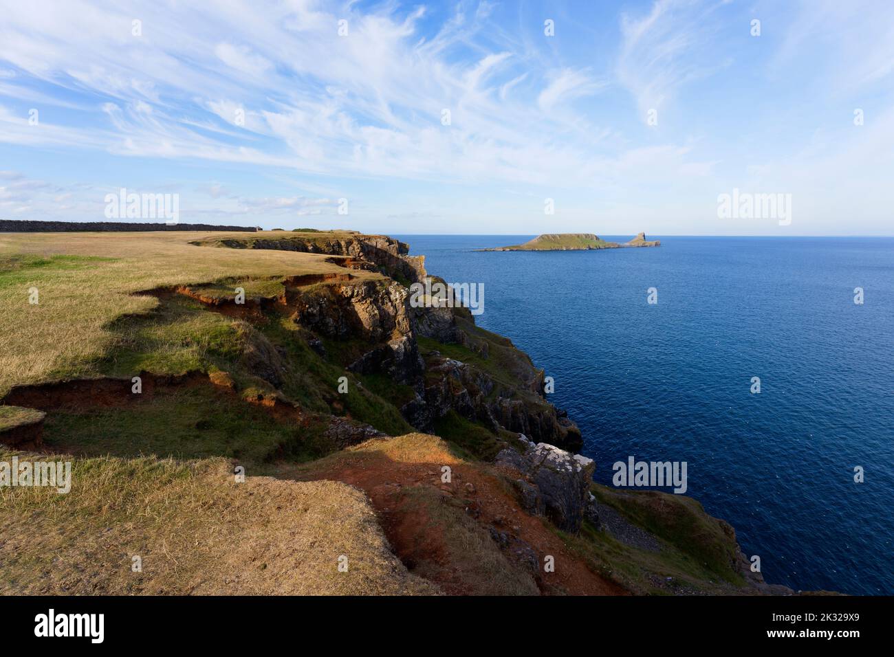 Along the grass covered clifftops of Rhossili Bay to the island known as Worms Head Stock Photo ...