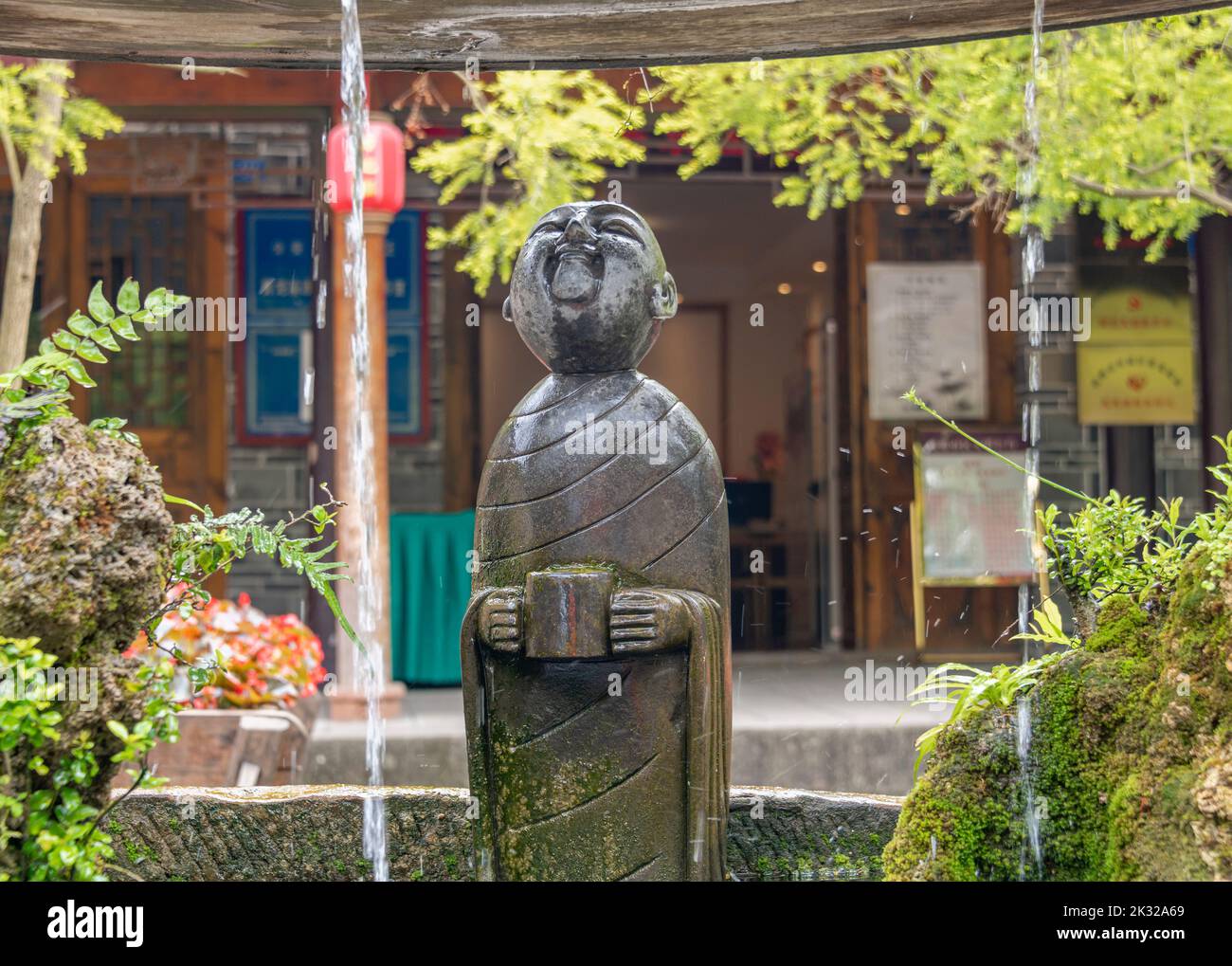An ancient stone figure faces a man-made waterfall at the ancient town ...