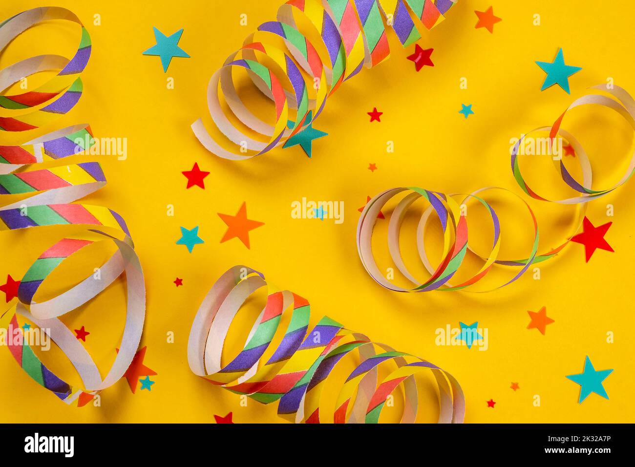 yellow background with colorful serpentine and star shaped confetti ...