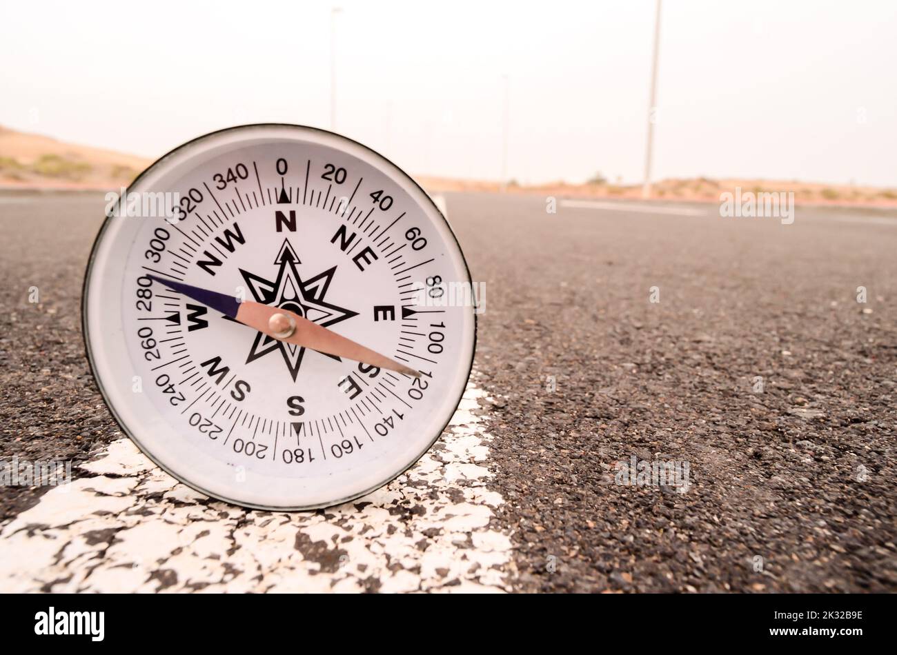 A closeup of a compass on an asphalt road - travel concept Stock Photo ...