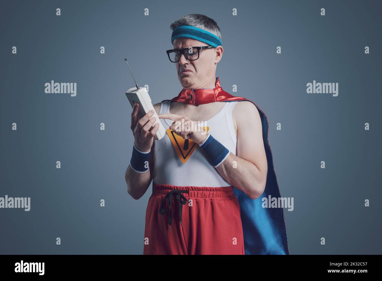 Funny nerdy superhero having problems with an old cordless telephone ...