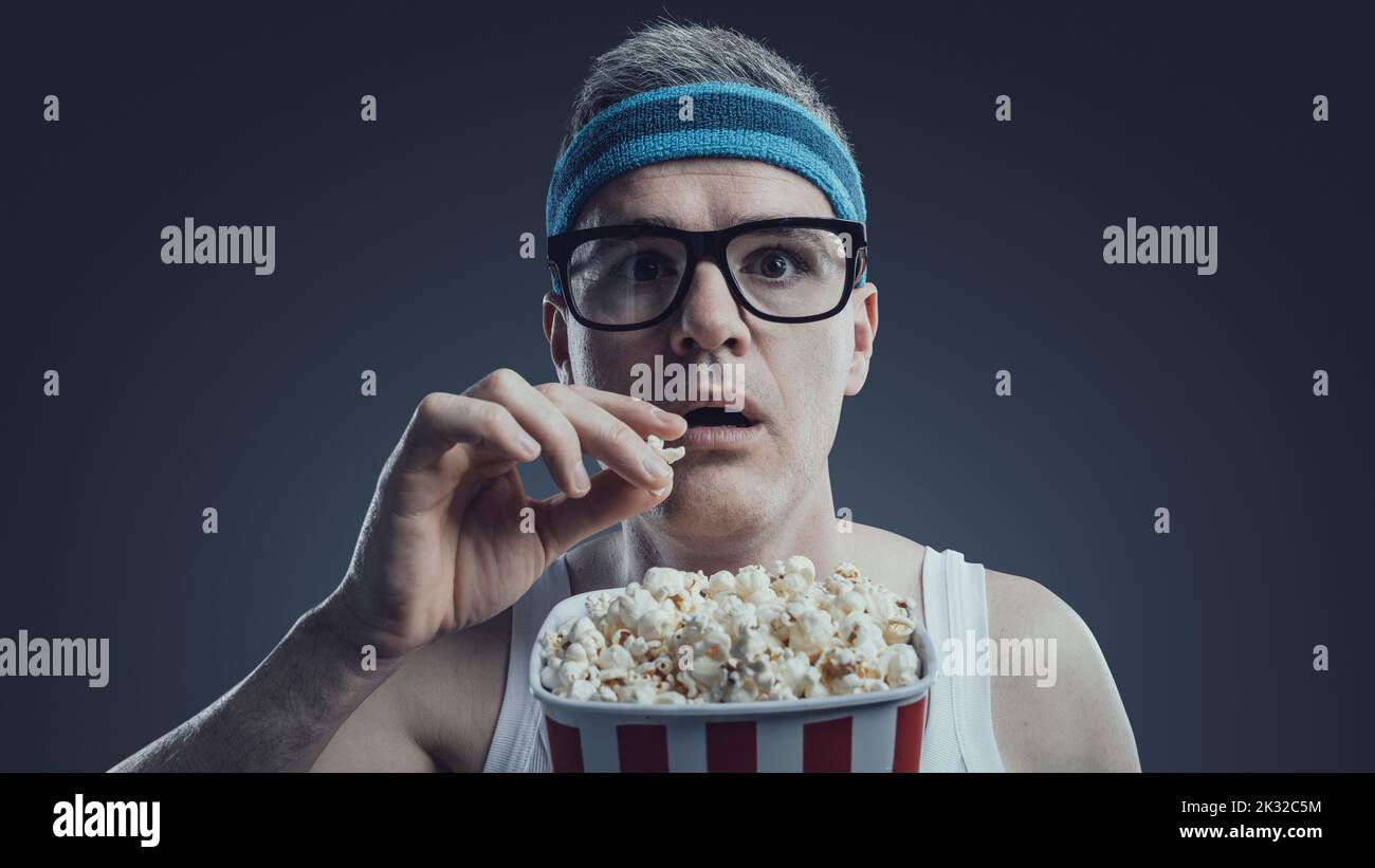 Funny guy with glasses and headband watching movies, he is staring at ...