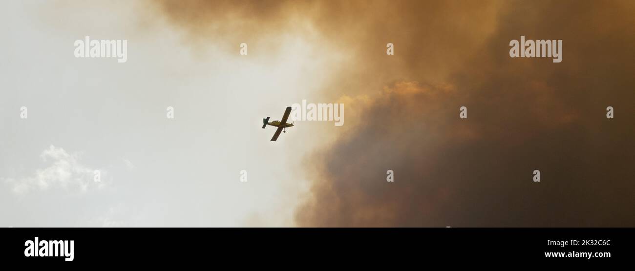 Firefighting plane flying into a large cloud of smoke caused by a ...