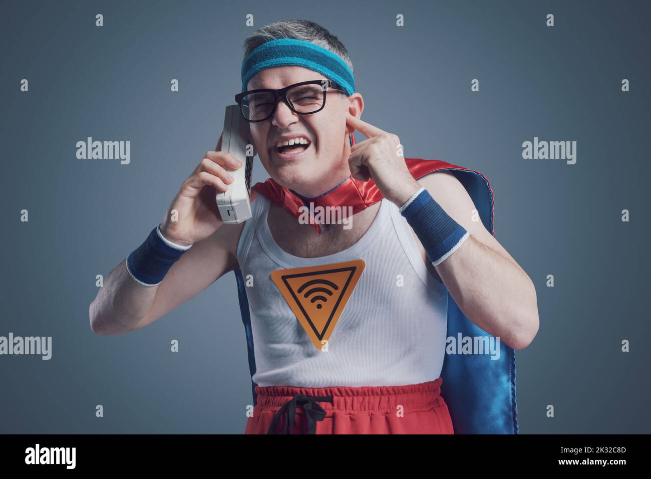 Funny superhero making a phone call using an old obsolete cordless ...